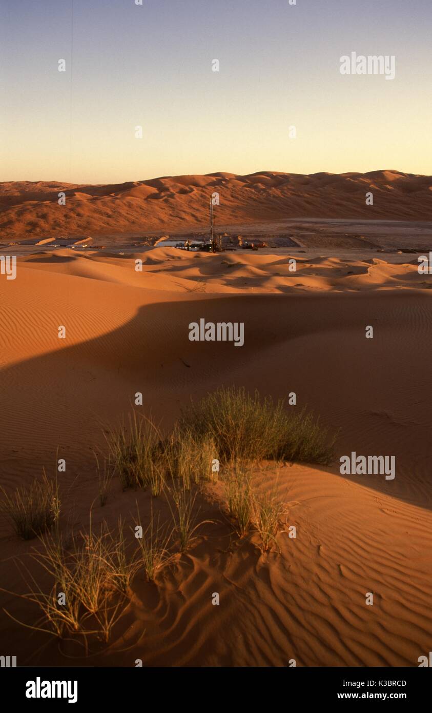 An oil rig searching for oil amongst the sand dunes that will feed into ...