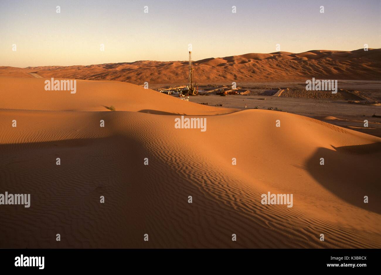 An oil rig searching for oil amongst the sand dunes that will feed into ...