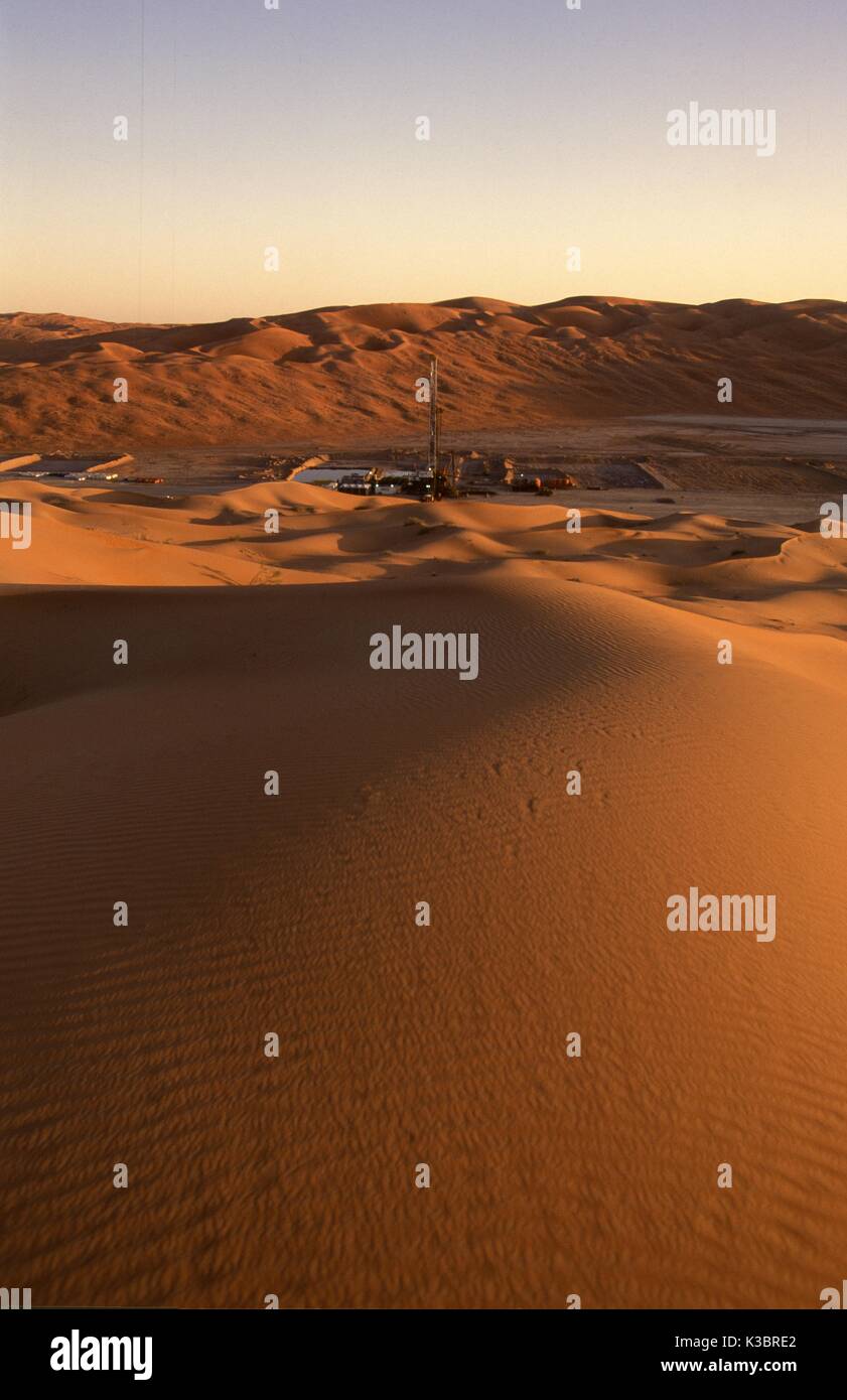 An oil rig searching for oil amongst the sand dunes that will feed into ...