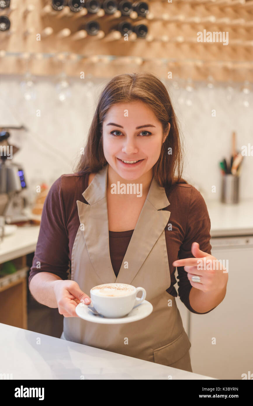 Happy female barista offering coffee to customer at cafe Stock Photo ...