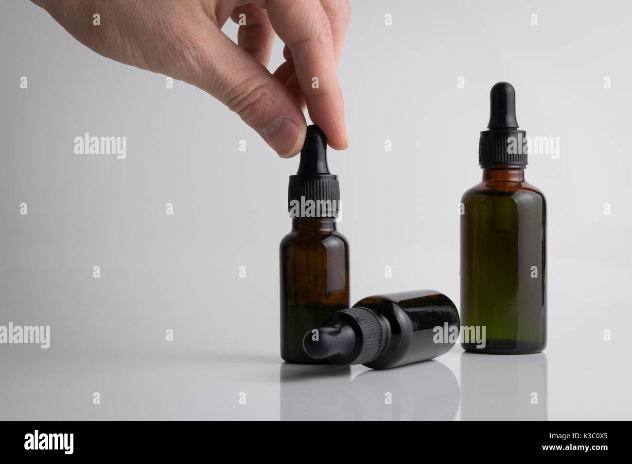Isolated hand holding a medical brown drop bottle over a white ...