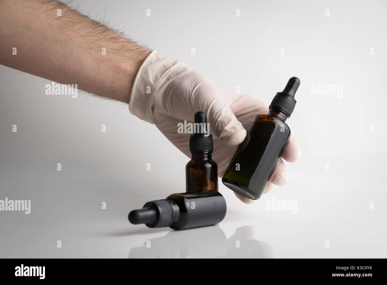 Isolated hand holding a medical brown drop bottle over a white ...