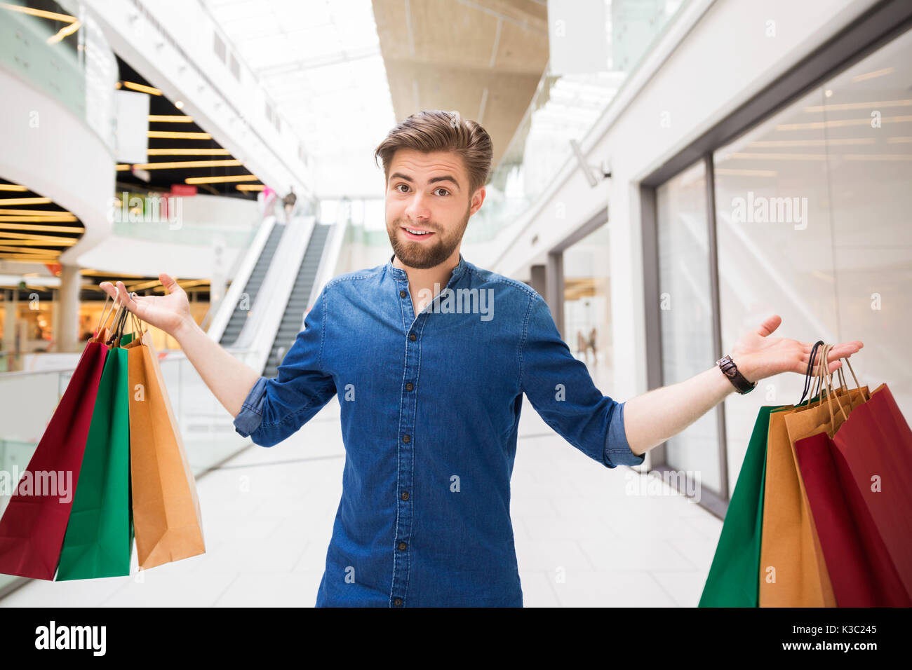 A photo of young, handsome man standing at the mall with loads of ...