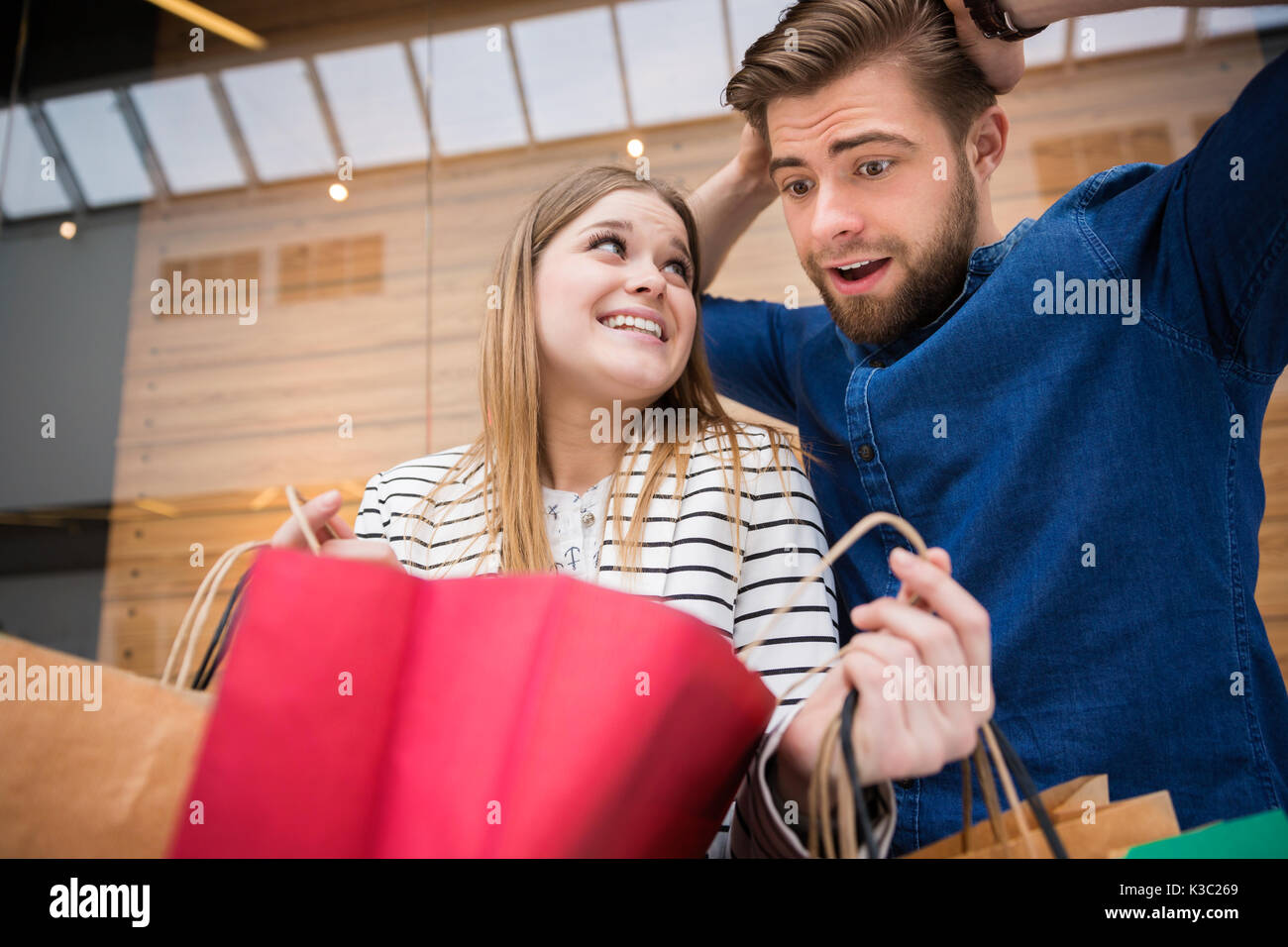 A photo of young woman showing her boyfriend what she bought. He's ...