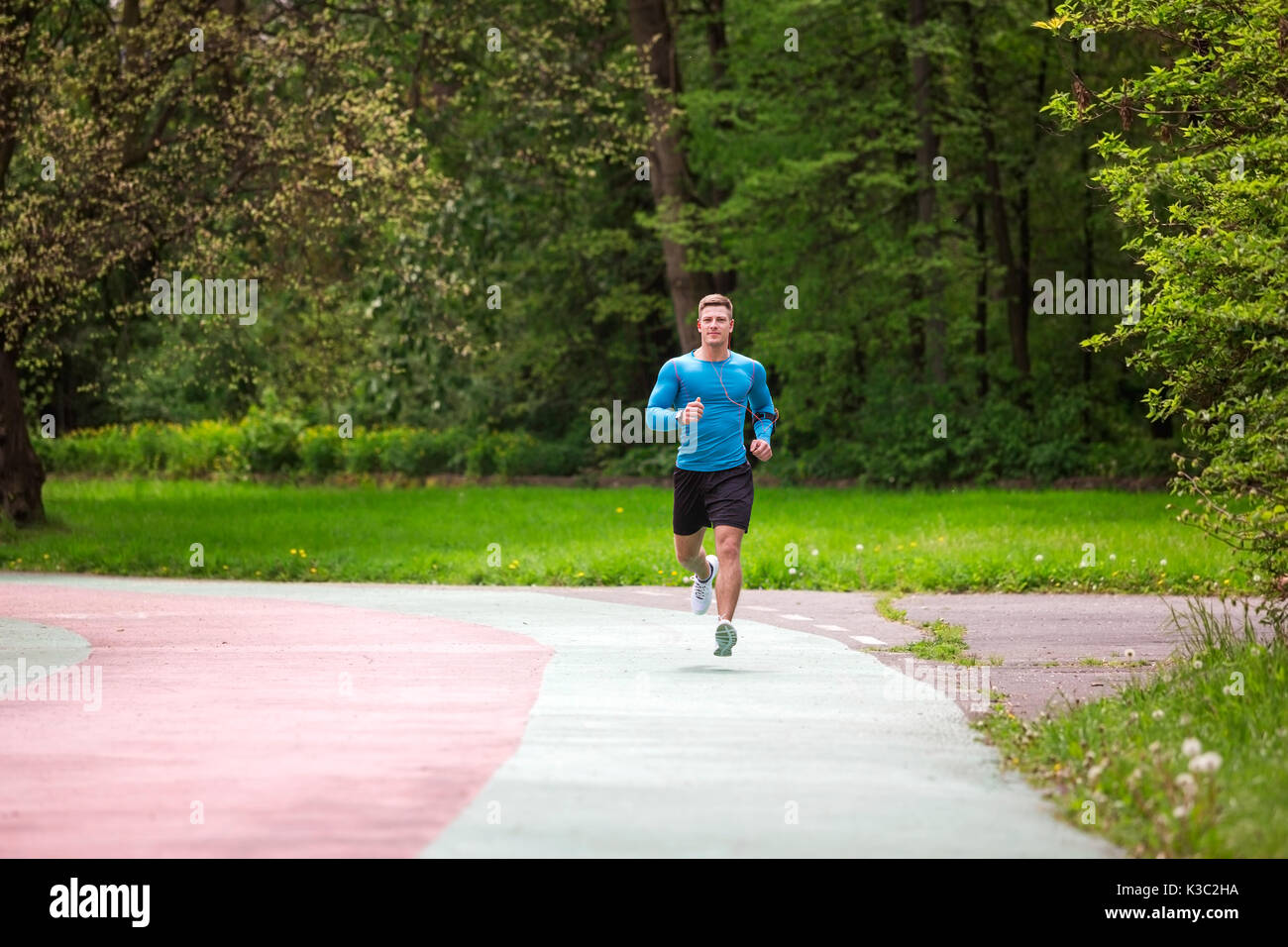 A photo of young, muscular man jogging on the racetrack Stock Photo - Alamy