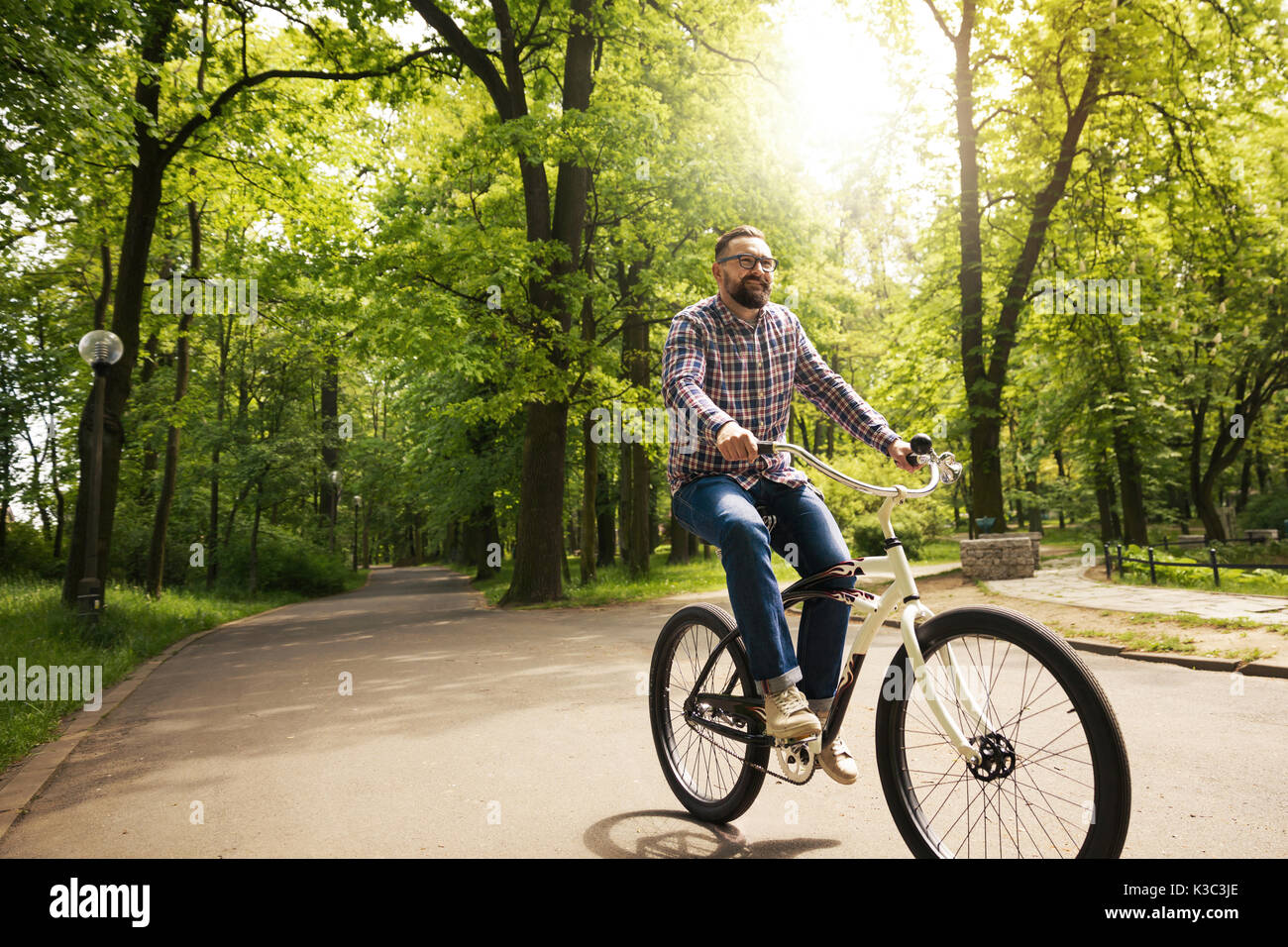 Portrait of young man riding bike on park path Stock Photo - Alamy
