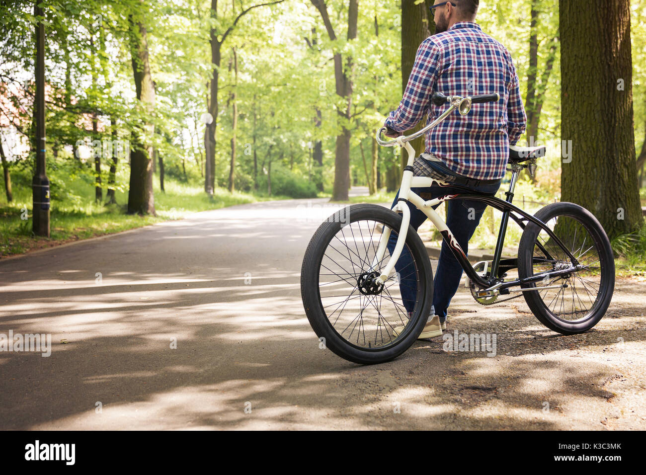 Rear portrait of modern man sitting on bike at park taking rest Stock ...