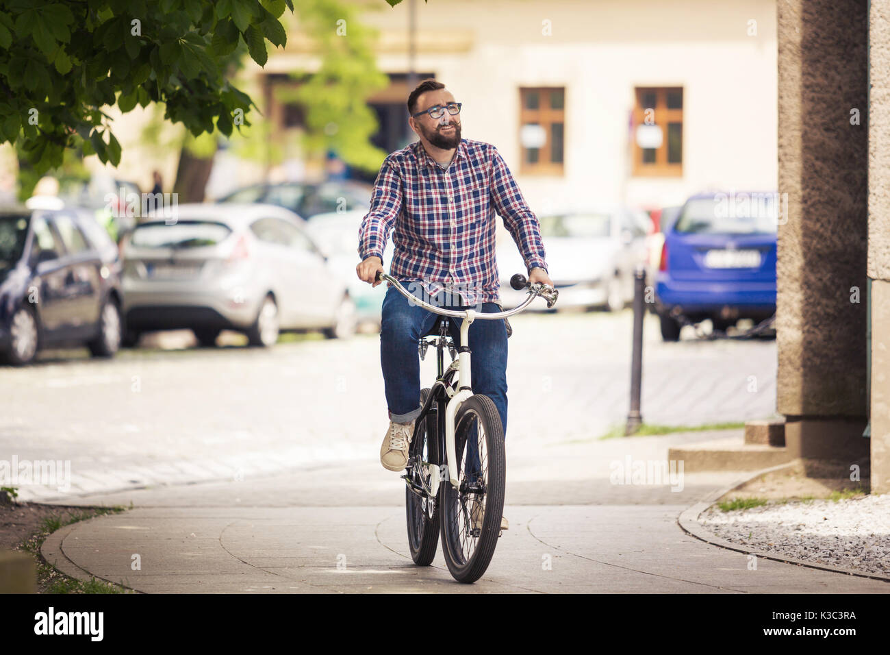 Portrait of young trendy man riding city bike on pavement Stock Photo ...