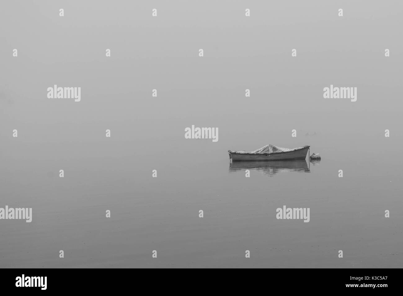 Boat on calm lake water in a foggy morning with other fishing boats in ...