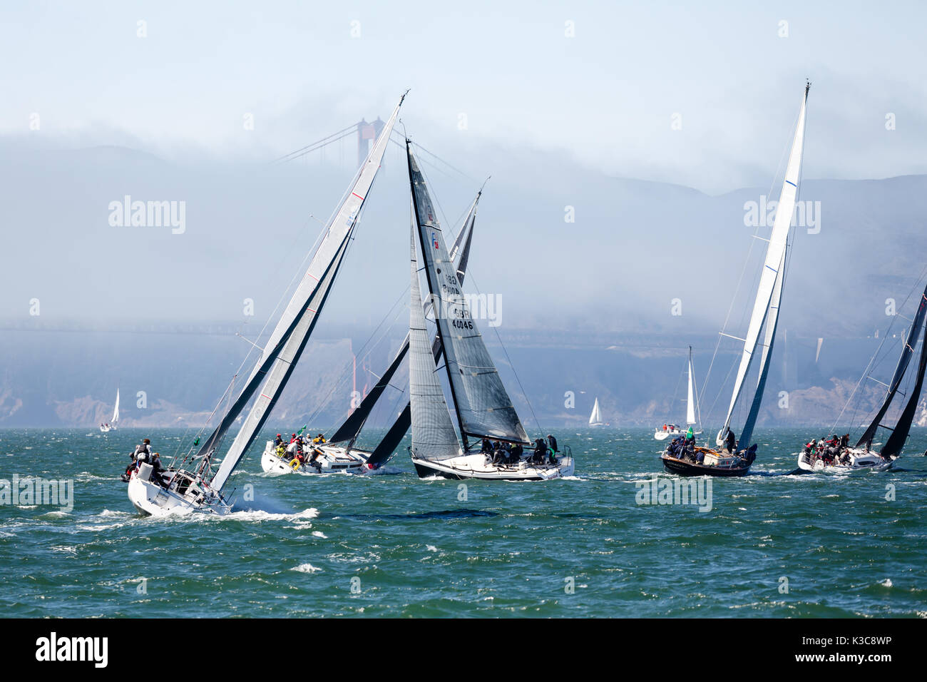 Five sailboats very close together try to cross the finish line first ...