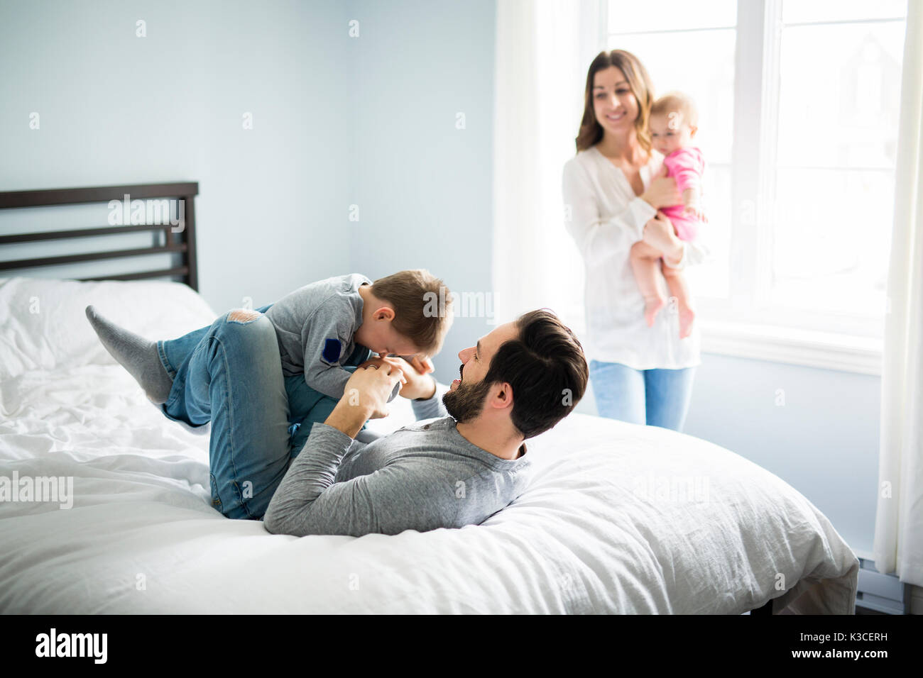 four peoples family on a white bed Stock Photo - Alamy