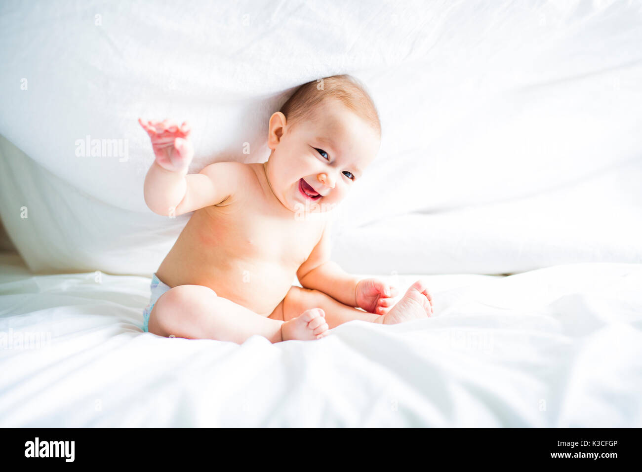 baby girl sit on white sheet Stock Photo - Alamy