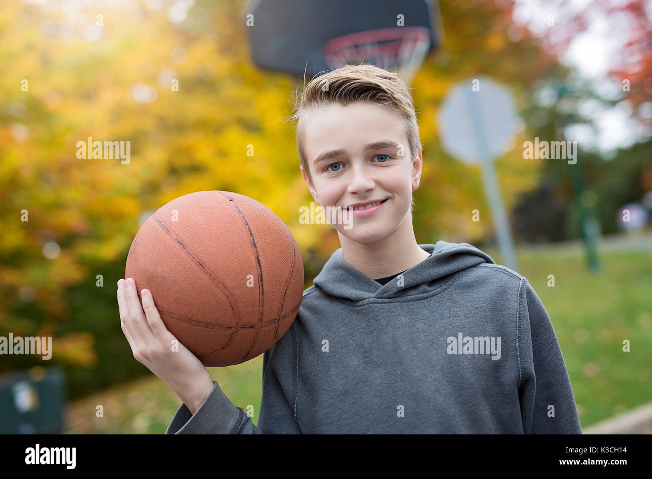 Boy alone during basketball game outside Stock Photo - Alamy