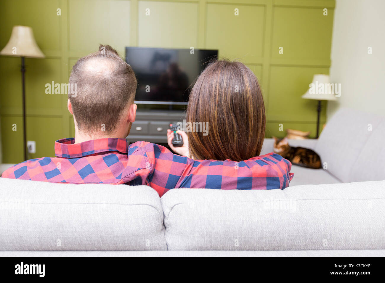 Beautiful couple watching TV sitting on couch at home Stock Photo - Alamy