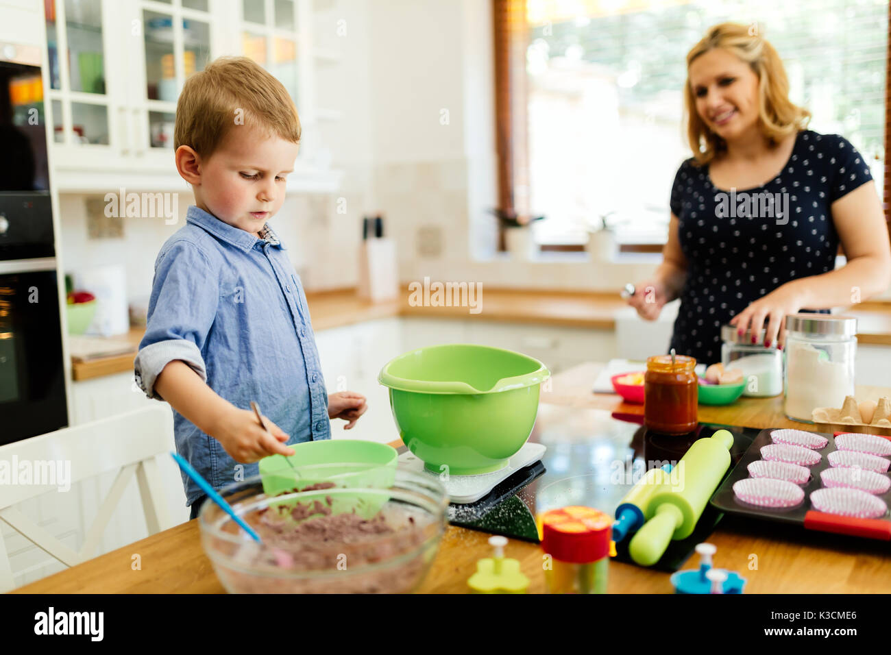 Smart cute child helping mother in kitchen Stock Photo - Alamy