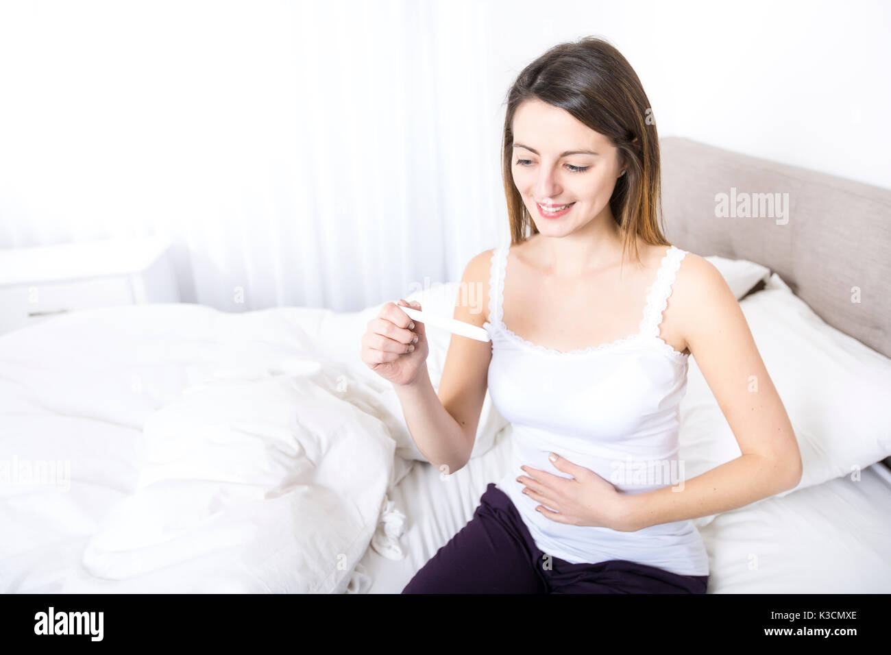 Young woman in bedroom at home wearing in white check pregnant test ...