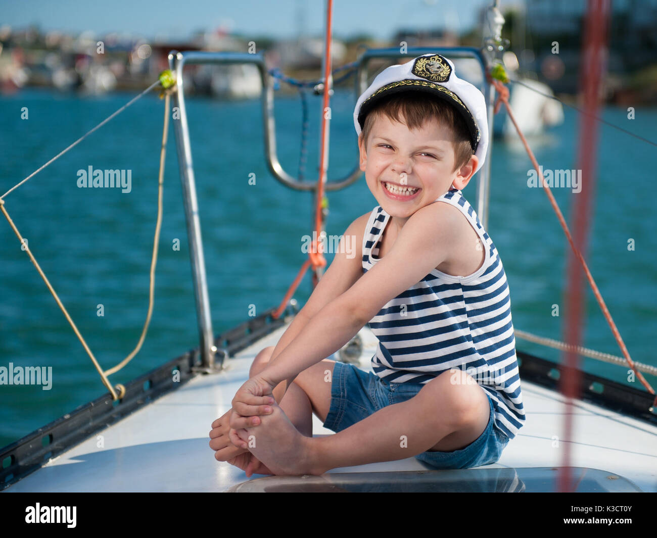 Happy smiling child captain on luxury yacht in a sea cruise in summer ...