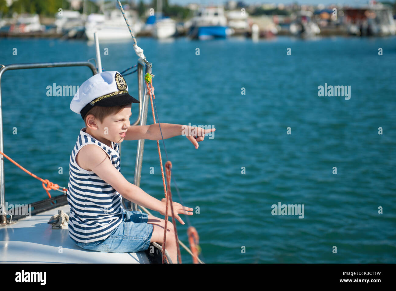 handsome little captain boy pointing with his finger to the distance ...