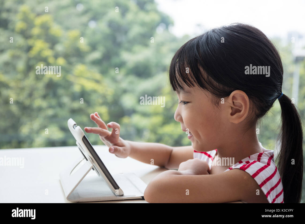 Asian Chinese little girl playing tablet computer at home Stock Photo ...