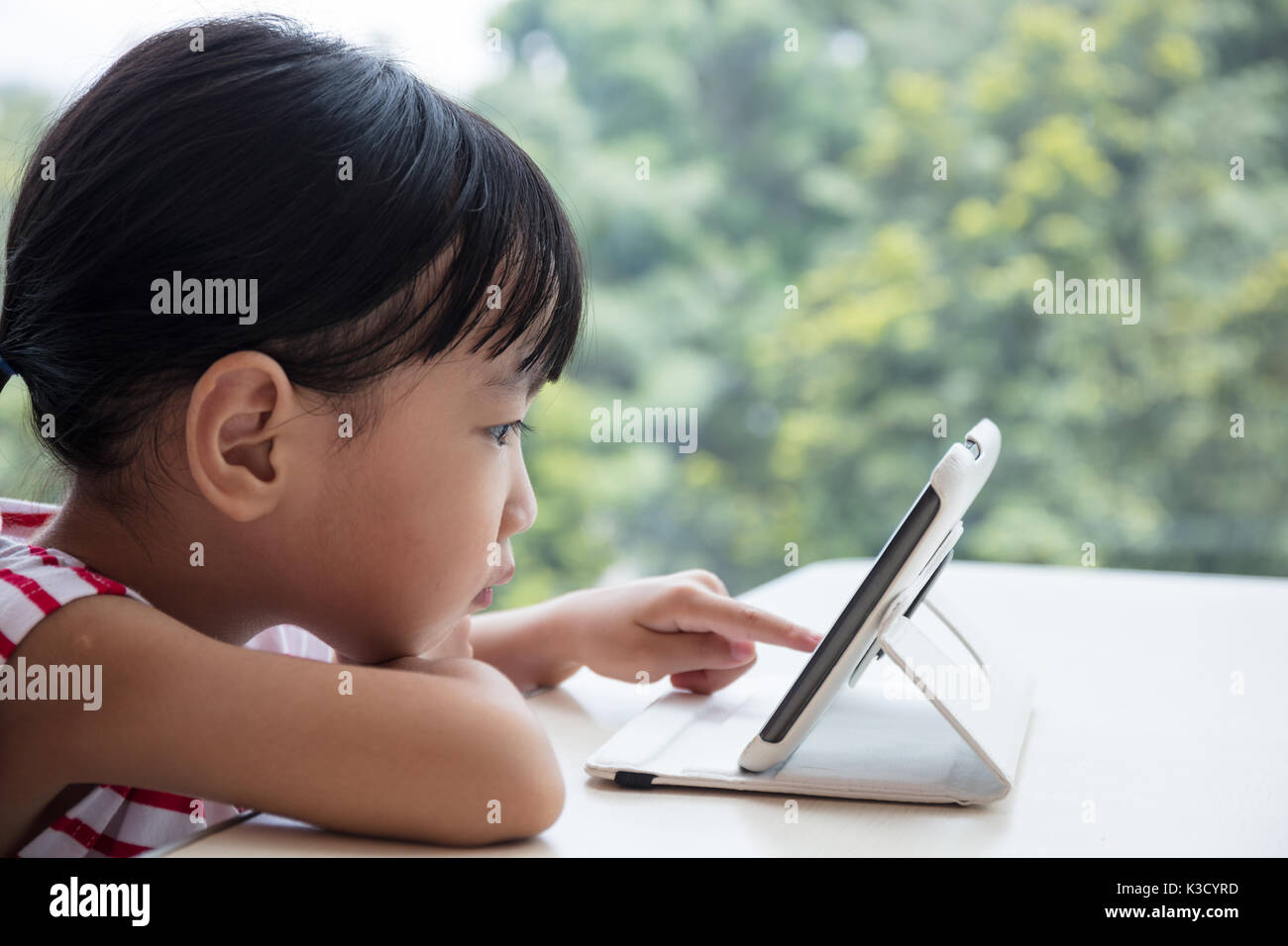 Asian Chinese little girl playing tablet computer at home Stock Photo ...