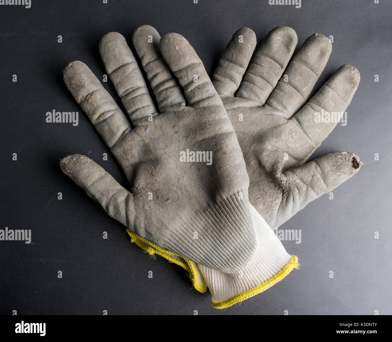 Isolated worn out working gloves against a black surface Stock Photo ...