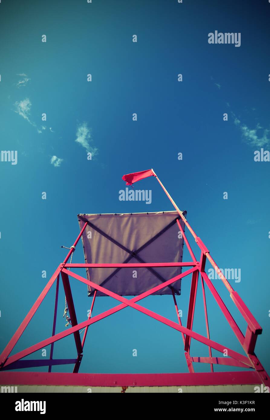 high turret of lifeguard on the beach with the red flag to signal the ...