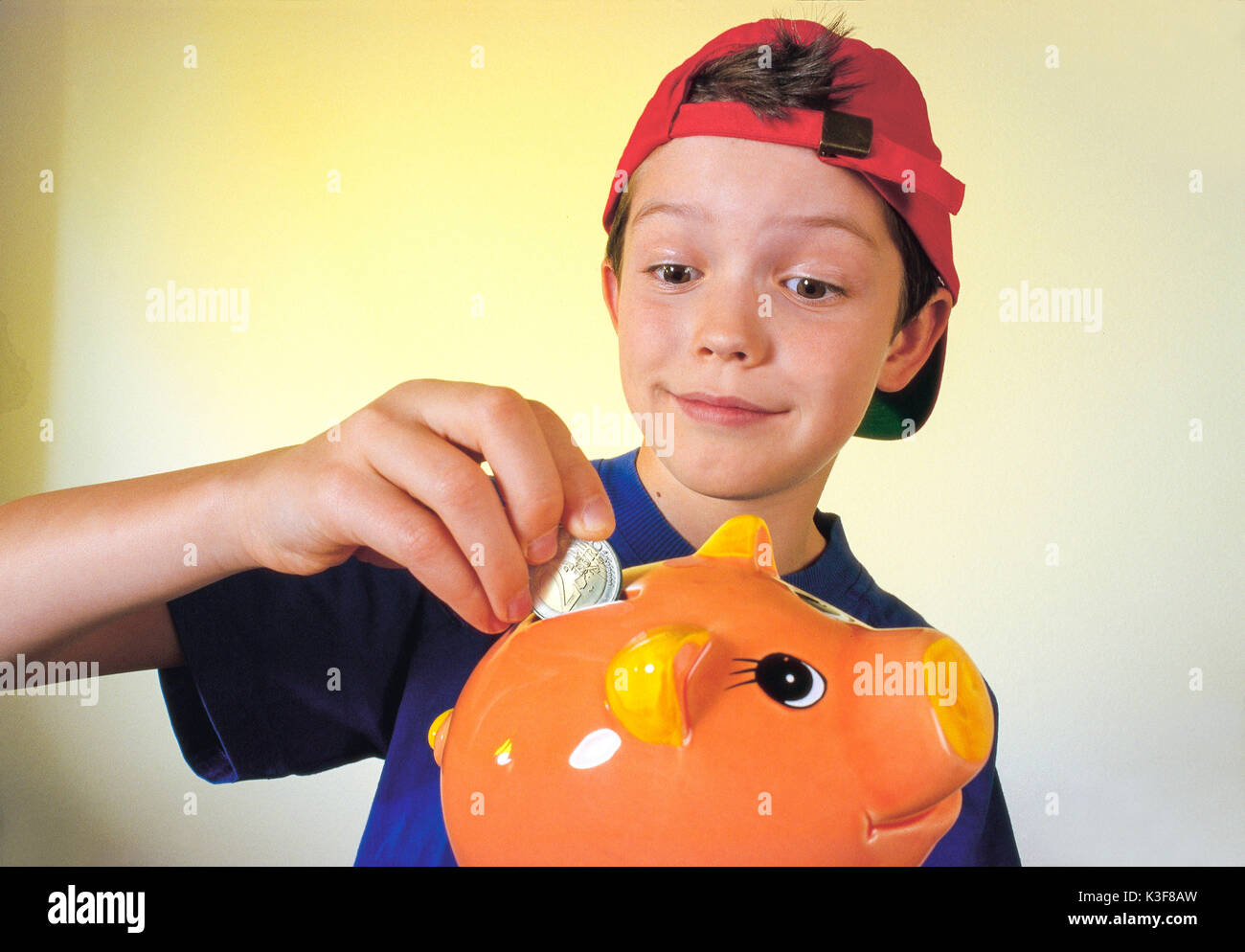 Small boy throws 2-euro-coin in a piggy bank Stock Photo - Alamy