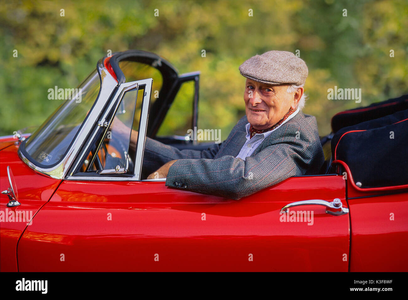 Senior sits in red old-timer Jaguar cabriolet Stock Photo - Alamy