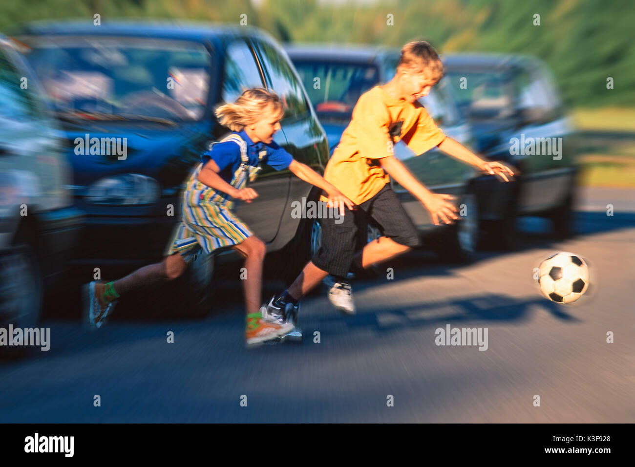 Boy and girl cross inattentively the street, running after a ball Stock ...