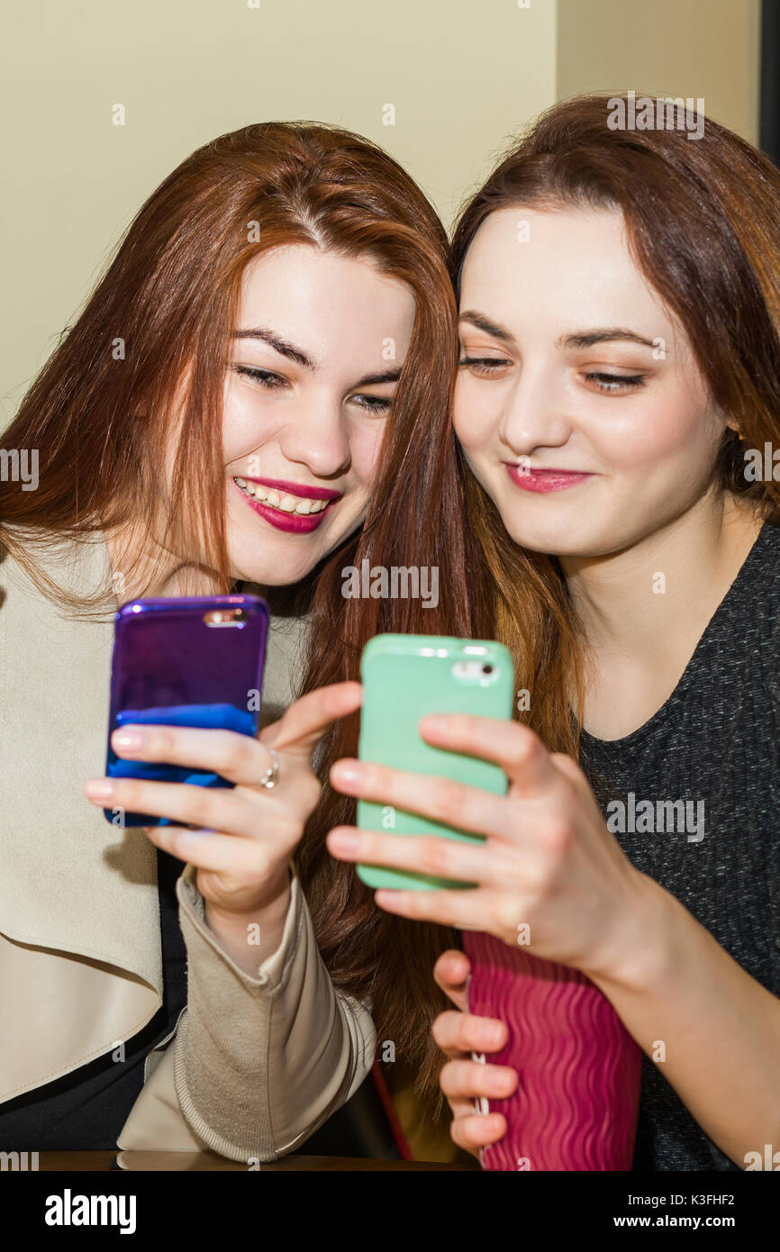 Girl showing mobile phone to a friend Stock Photo - Alamy