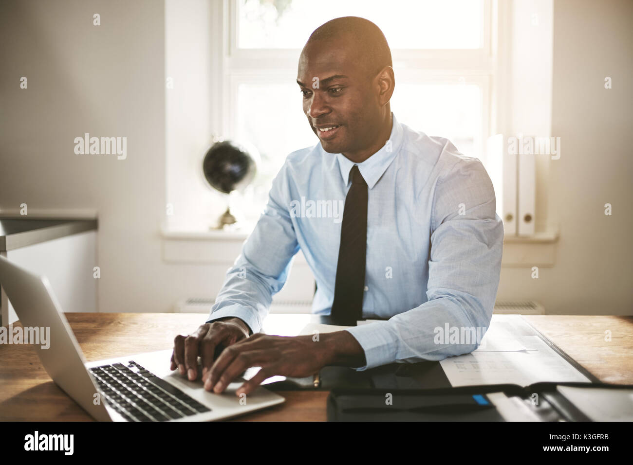 Successful young African executive sitting at his desk in an office ...