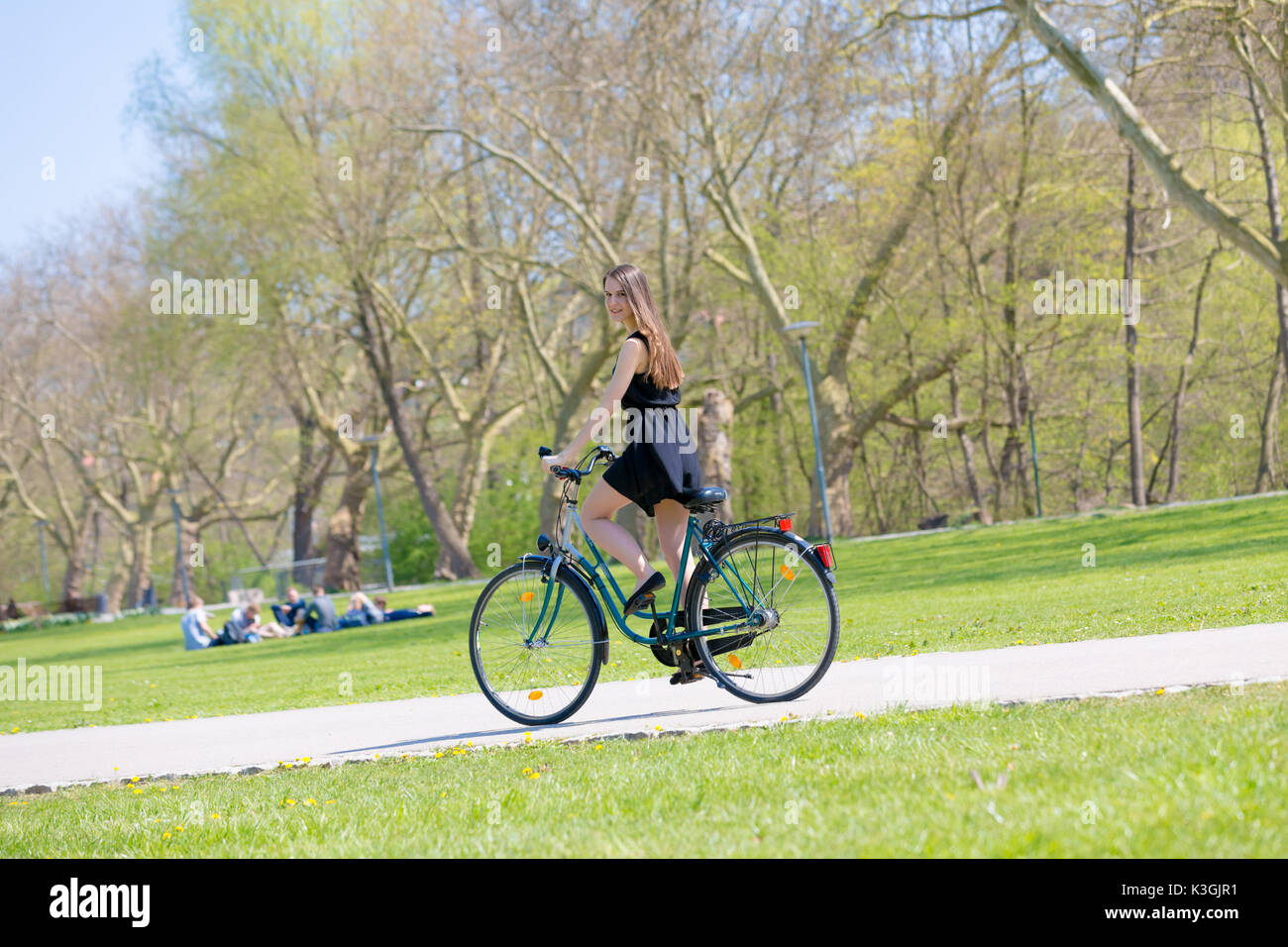Portrait view of girl on bicycle wearing on black short dress. Young ...