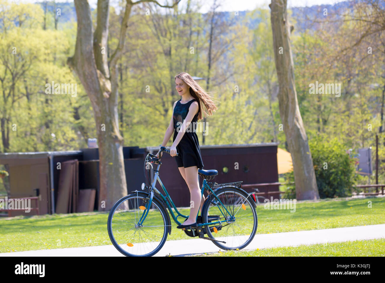 Portrait view of girl on bicycle wearing on black short dress. Young ...