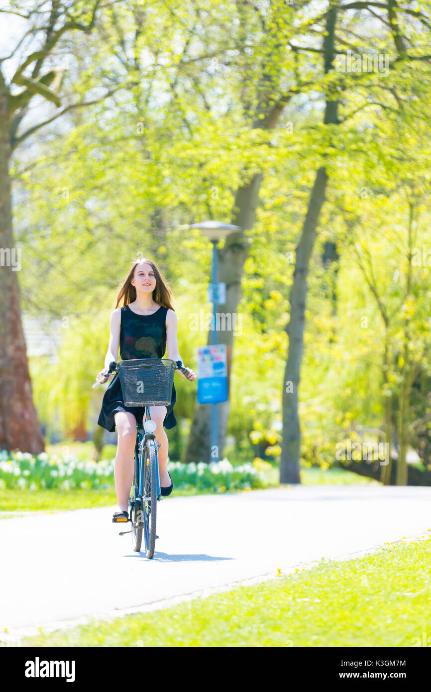 Portrait view of girl on bicycle wearing on black short dress. Young ...
