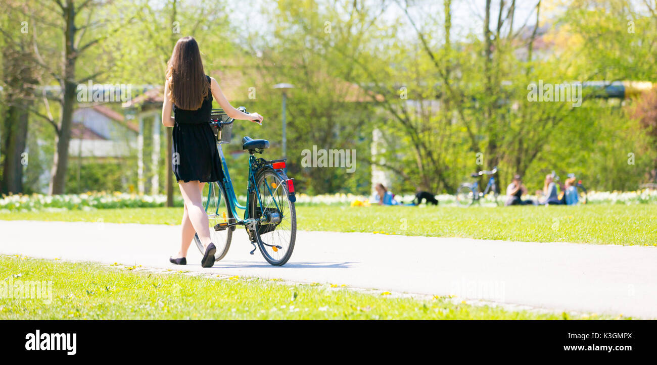 Back view of girl on bicycle wearing on black short dress. Young Woman ...