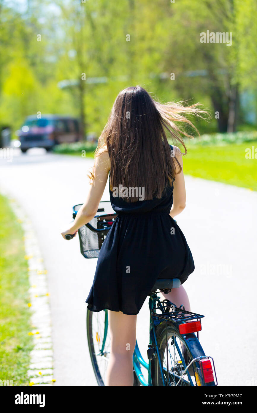 Back view of girl on bicycle wearing on black short dress. Young Woman ...
