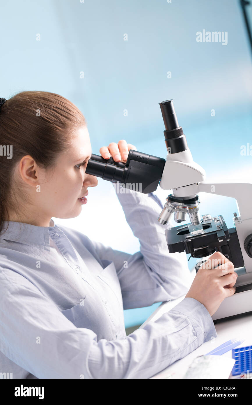 Doctor woman working a microscope. Female scientist looking through a ...