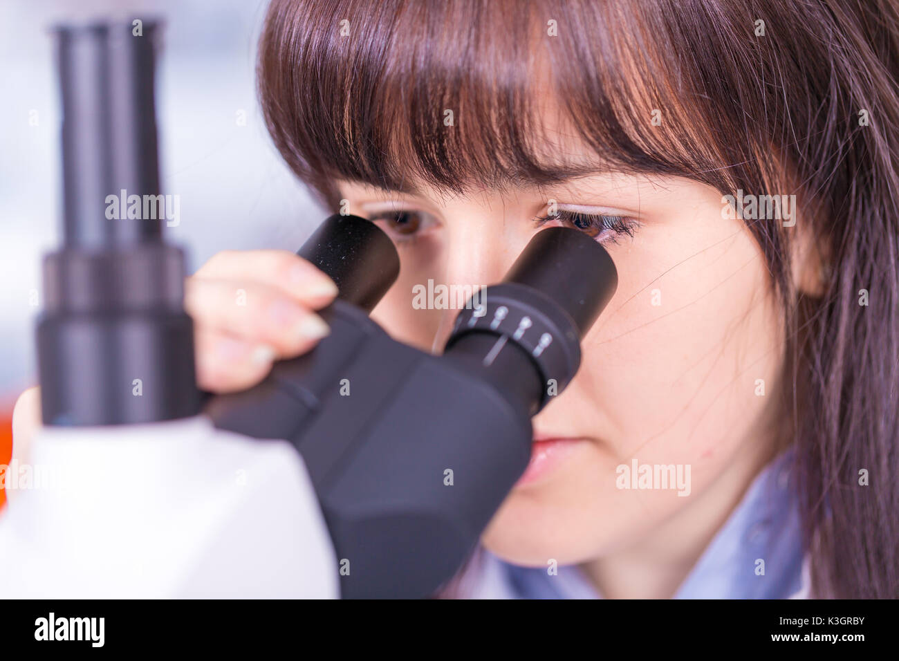 Doctor woman working a microscope. Female scientist looking through a ...