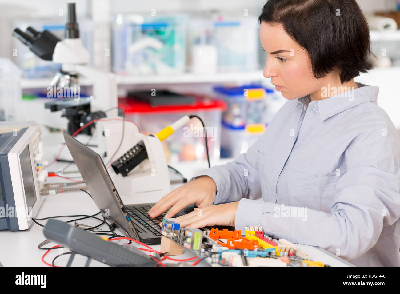 Female laboratory assistant Repairs PCB module for CNC robotics ...