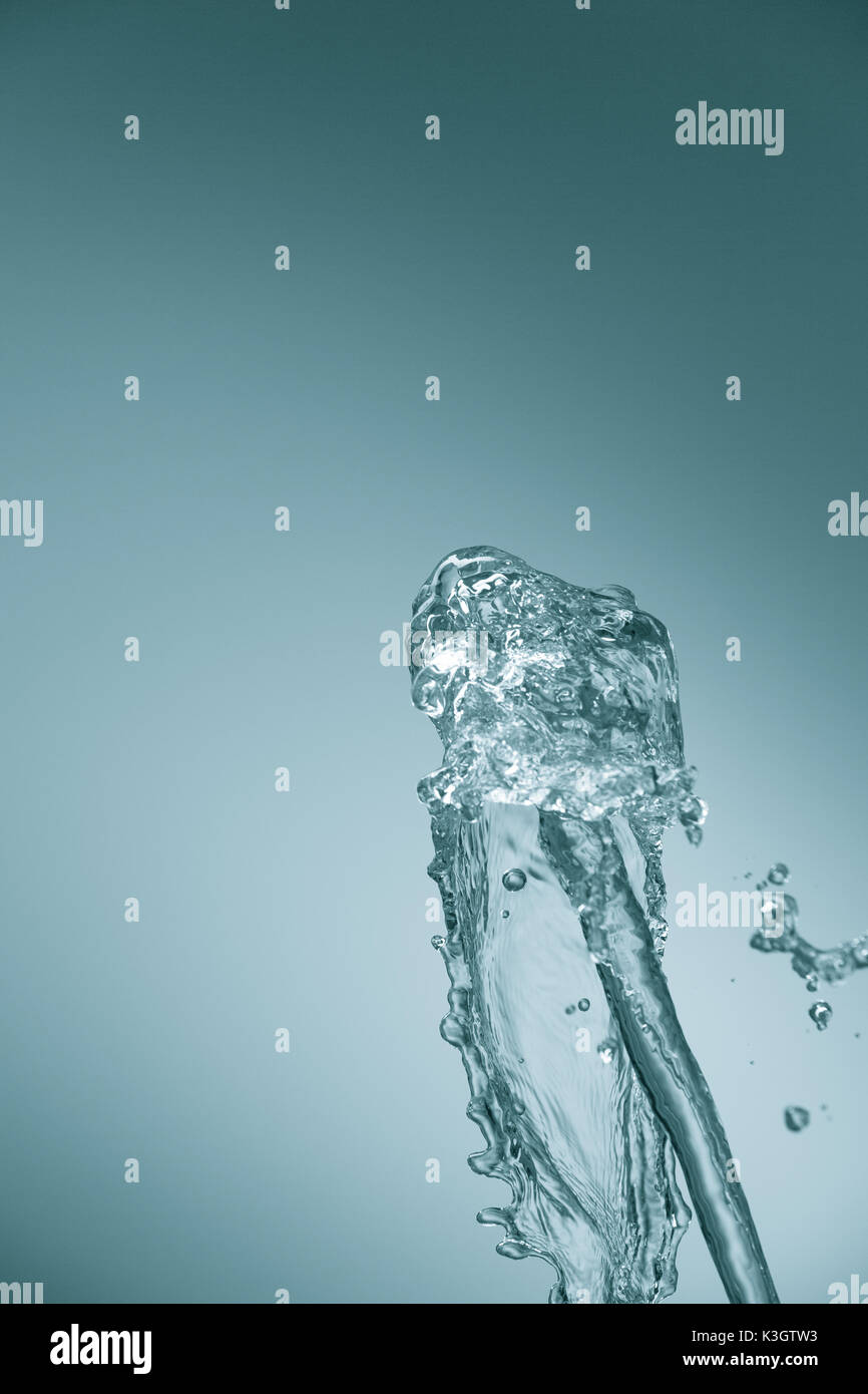 A stream of filtered natural water on a blue background. Splash of ...