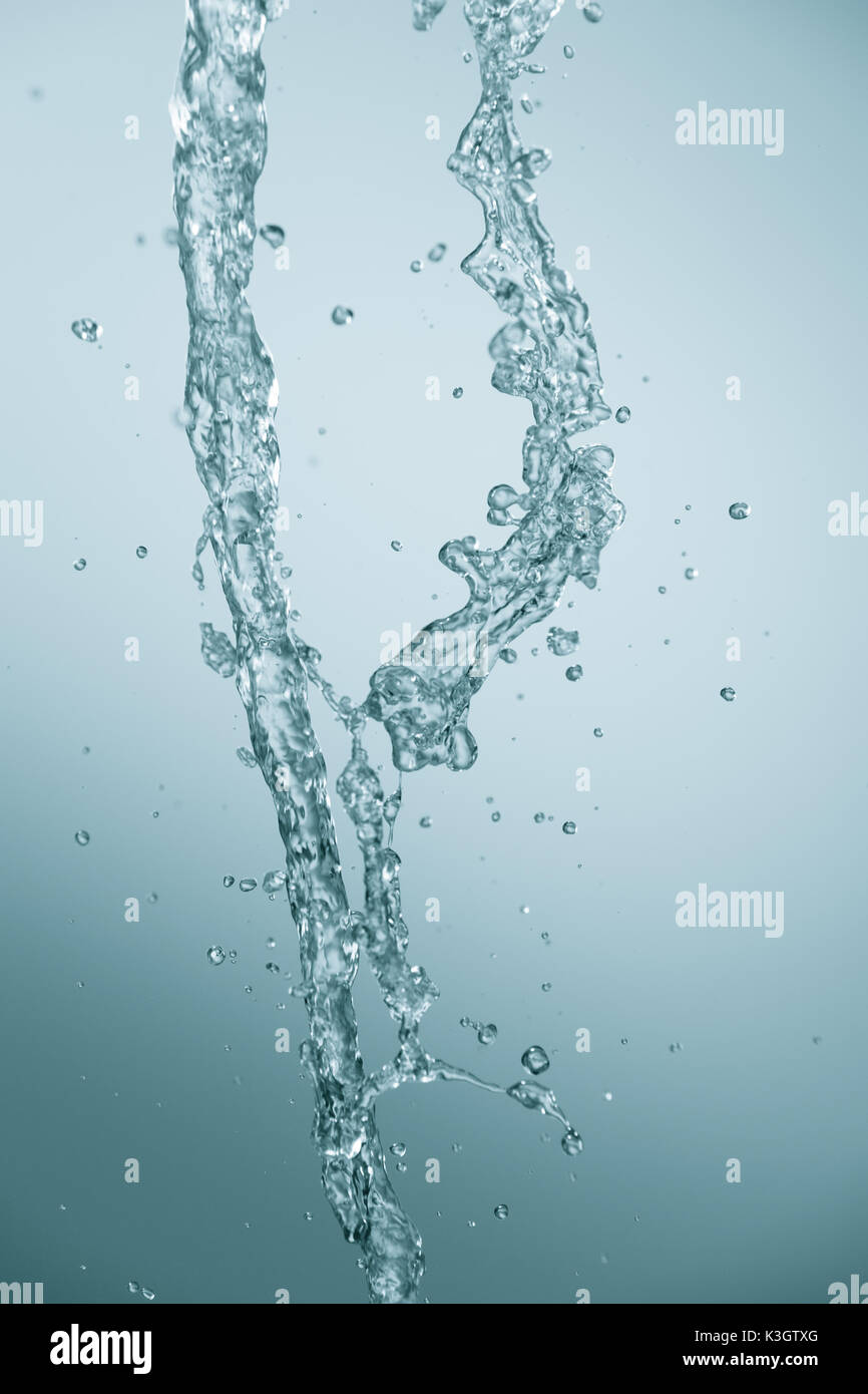 A stream of filtered natural water on a blue background. Splash of ...