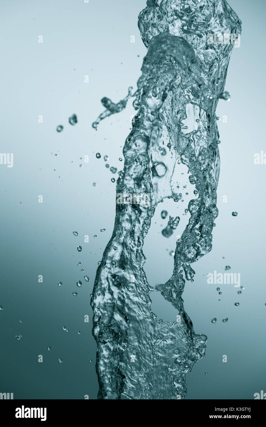 A stream of filtered natural water on a blue background. Splash of ...