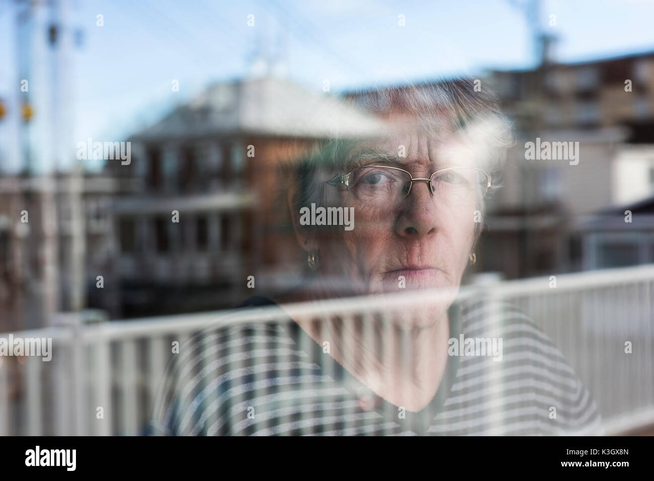 Senior woman looking out through a window like depress Stock Photo - Alamy