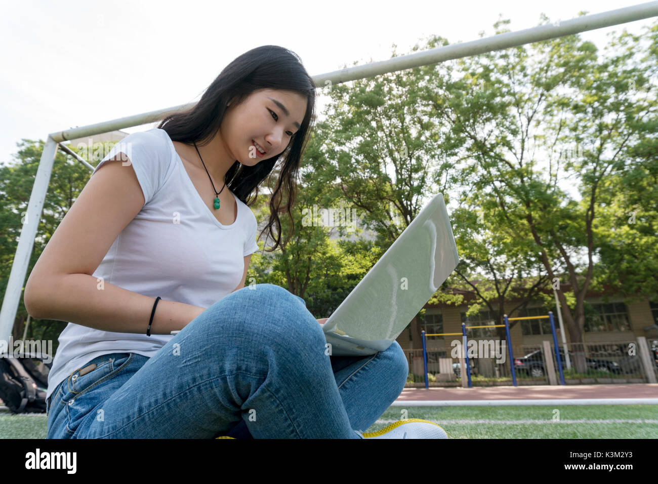Beautiful Asian college student with laptop ,Sat on the playground ...