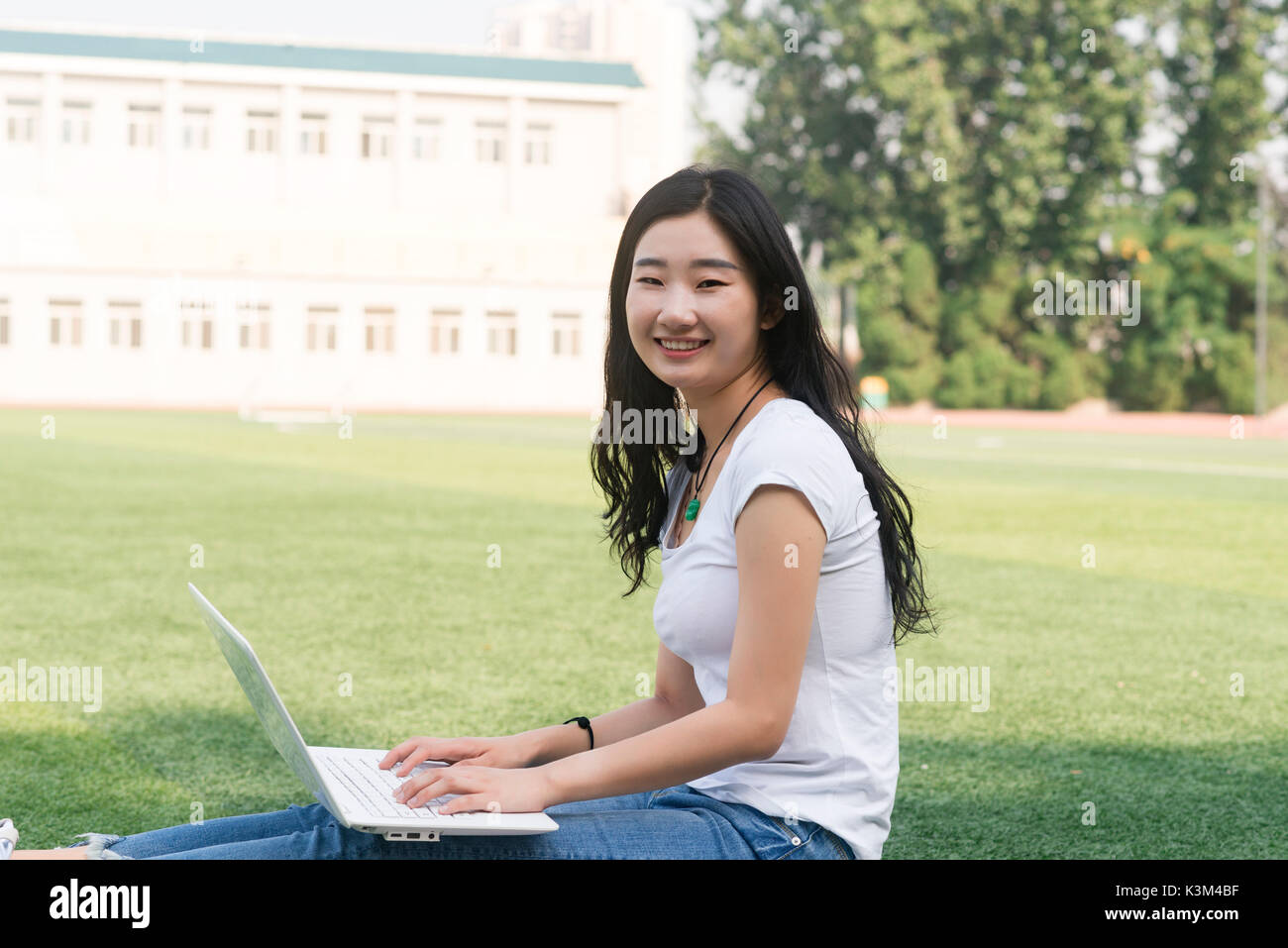 Beautiful Asian college student with laptop ,Sat on the playground ...