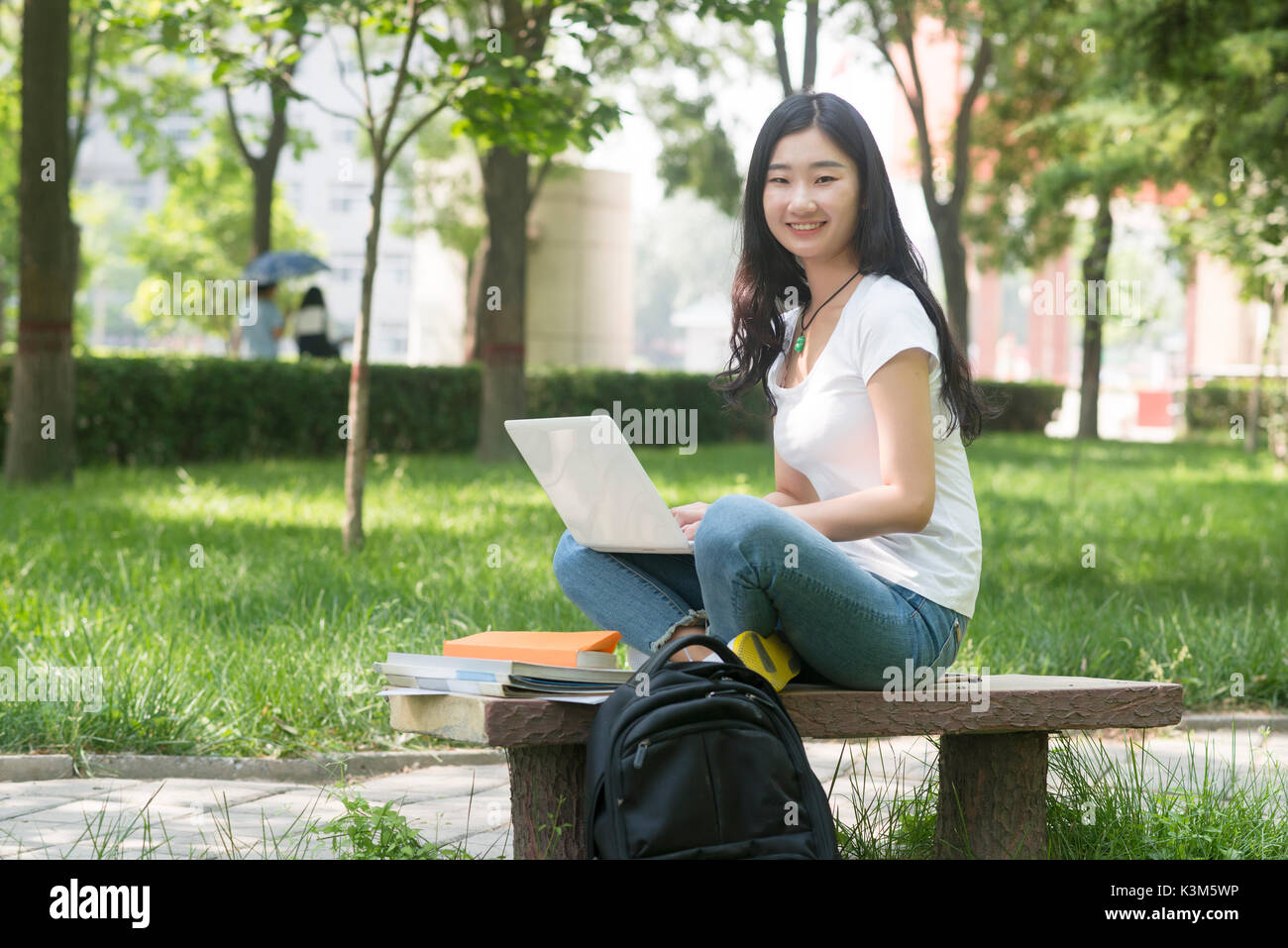 Beautiful Asian college student with laptop ,Sitting on the campus ...