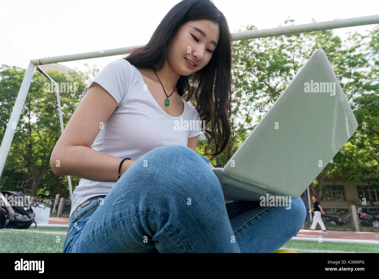 Beautiful Asian college student with laptop ,Sat on the playground ...