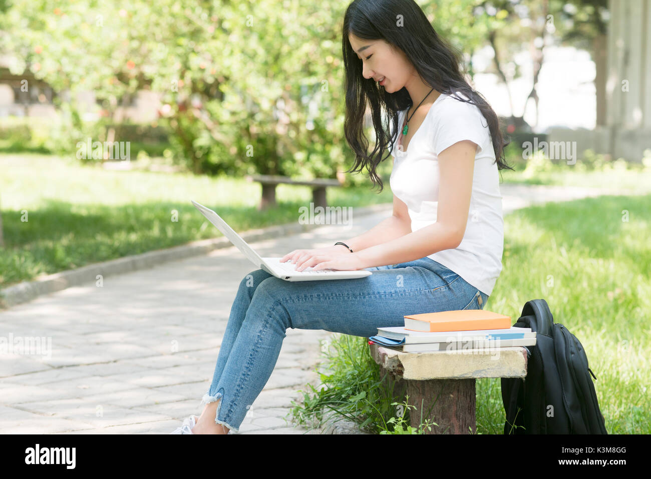 Beautiful Asian college student with laptop ,Sitting on the campus ...