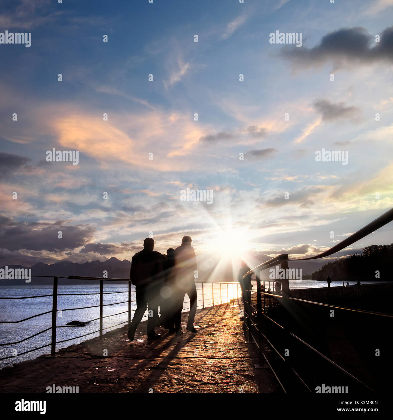 silhouetted people walking on street over sunset sky with sunbeam Stock ...