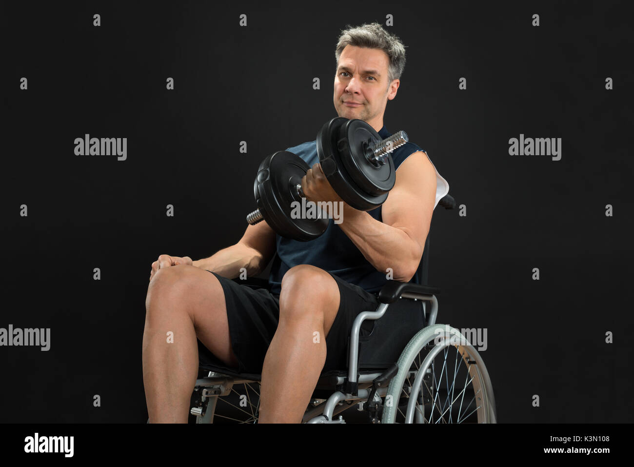 Handicapped Man On A Wheelchair Working Out With Dumbbell Over Black ...